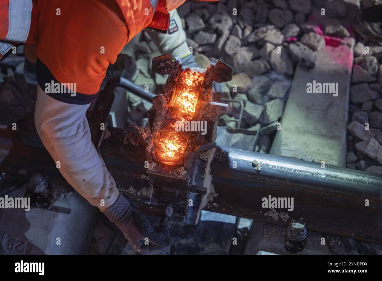 Welding work on a rail with sparks, worker handling tools, intense ...