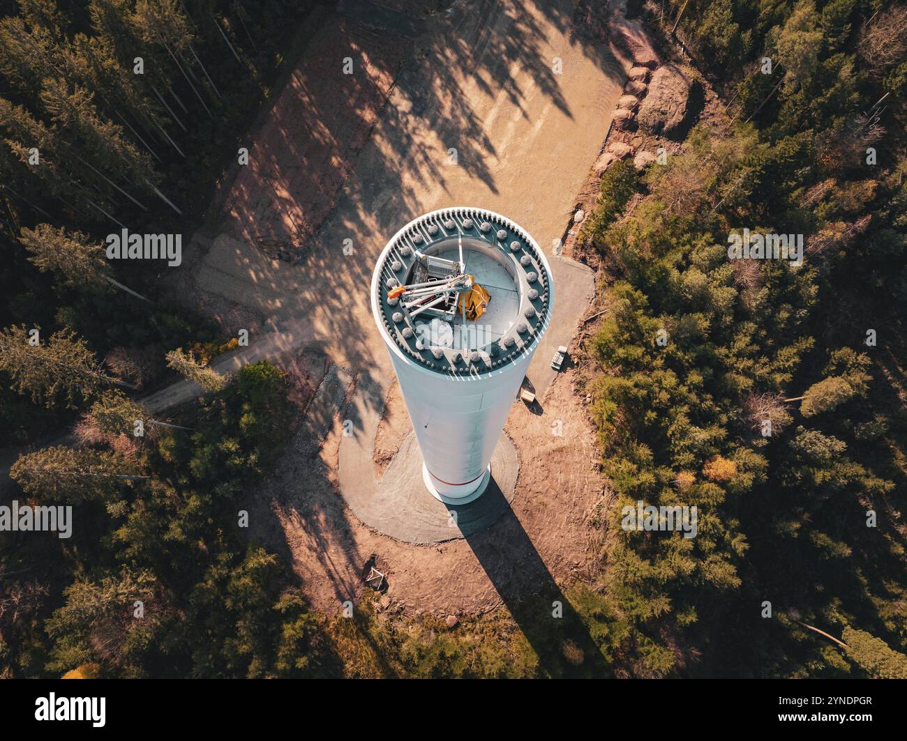 Sunlit wind turbine under construction with shadow cast, embedded in a ...