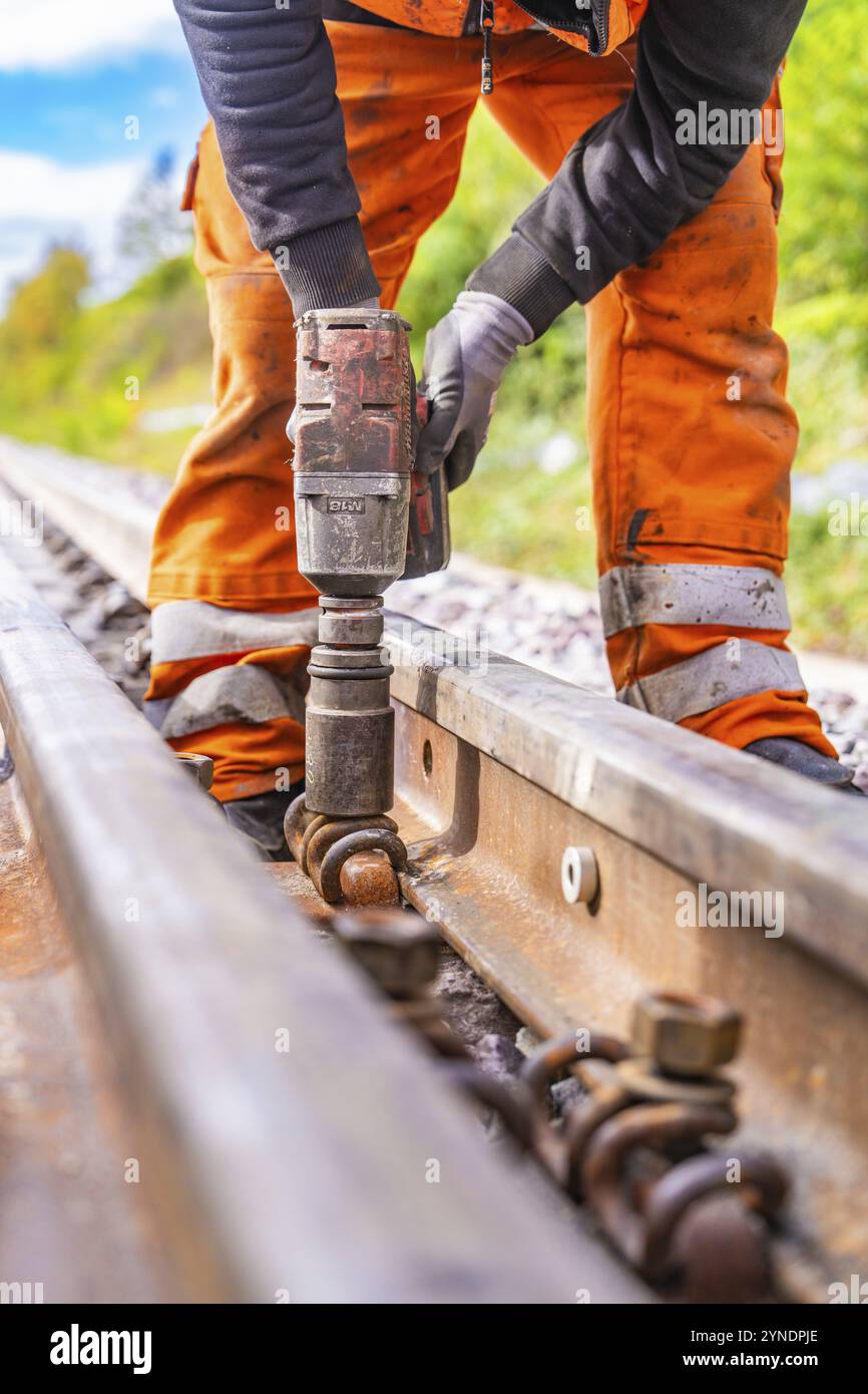 A construction worker uses a tool to fix the railway rails on the track ...