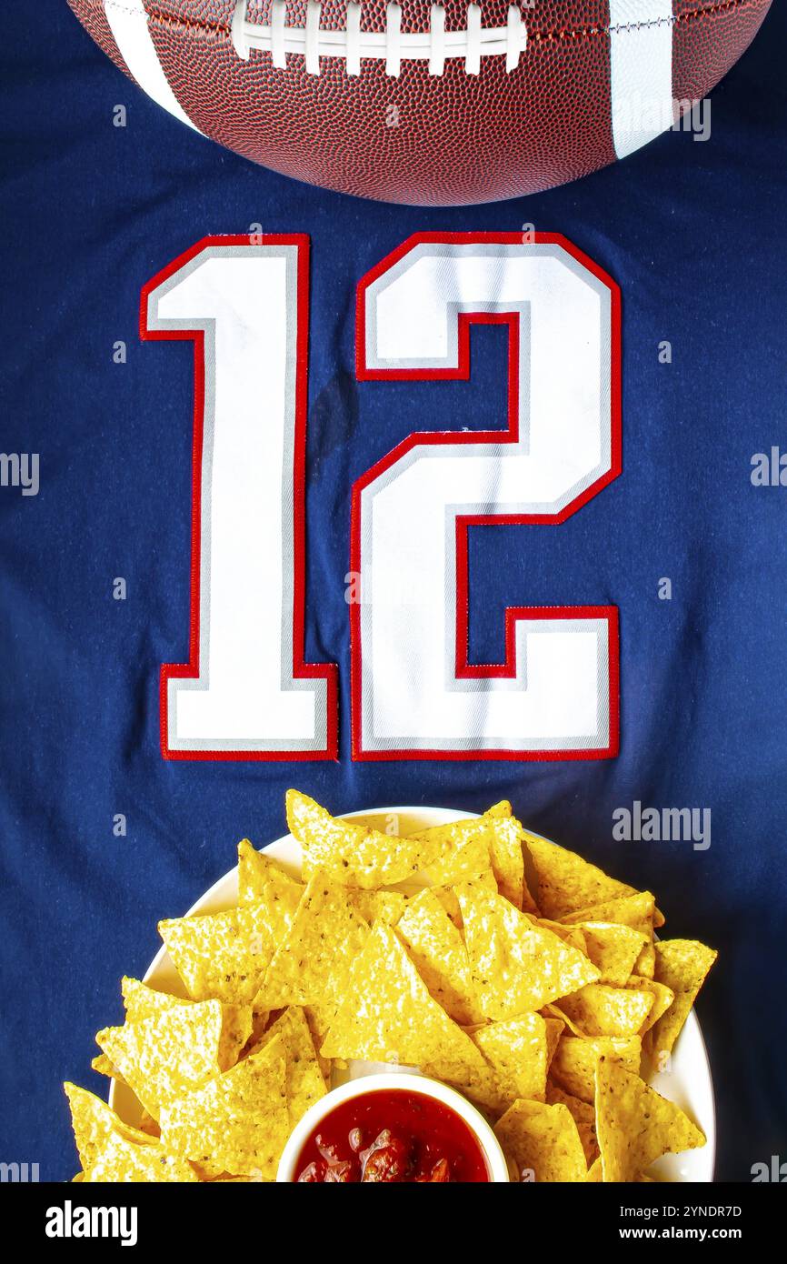 An American football with organic nacho chips and mild salsa on a white ...