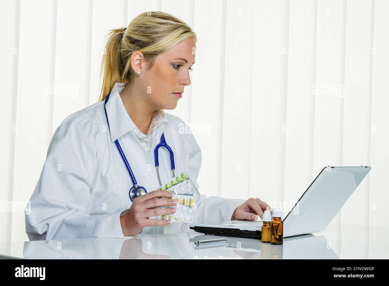 A blonde doctor with a stethoscope prescribing medication, computer ...