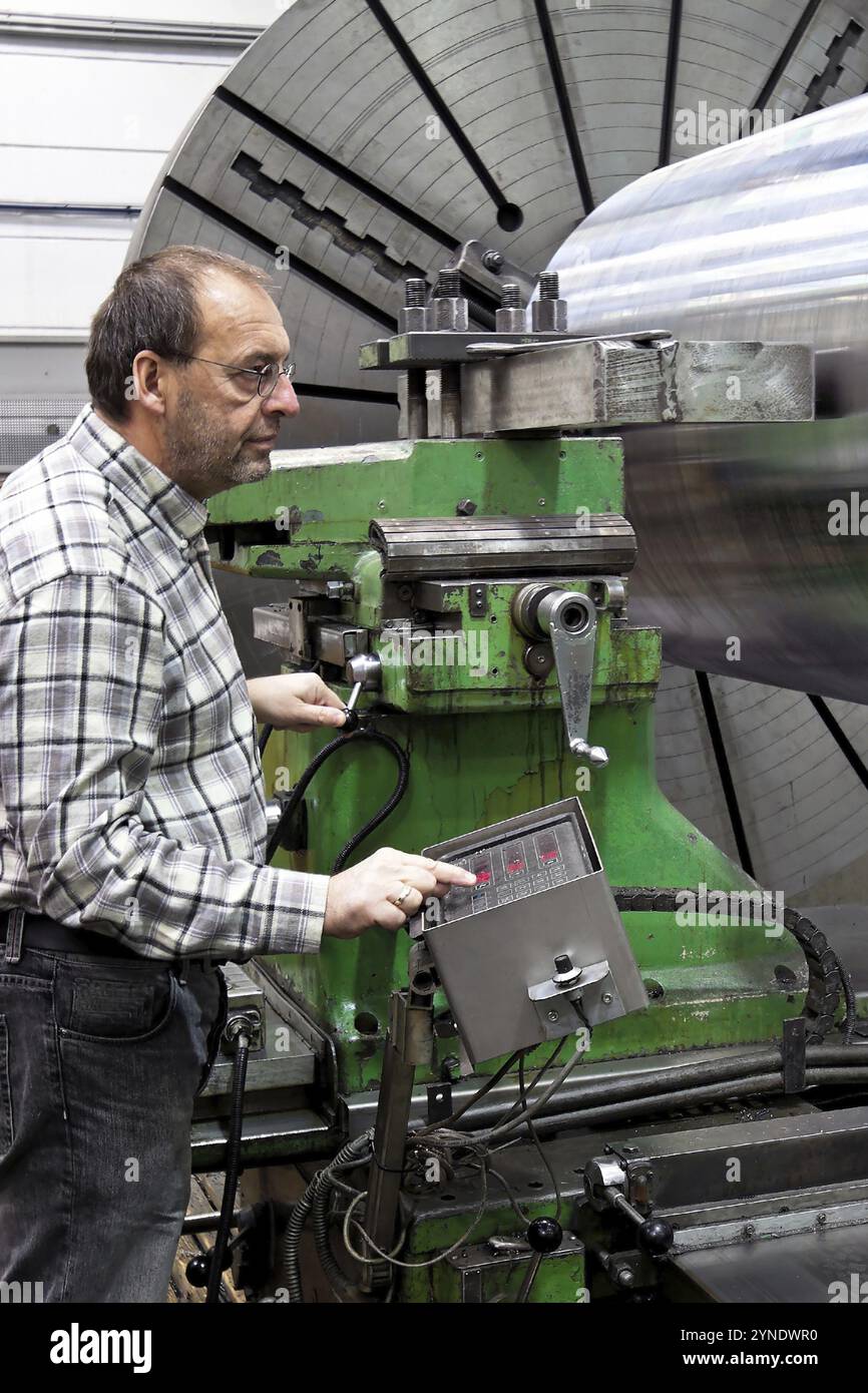 An older employee in the metal industry works on a CNC milling machine ...