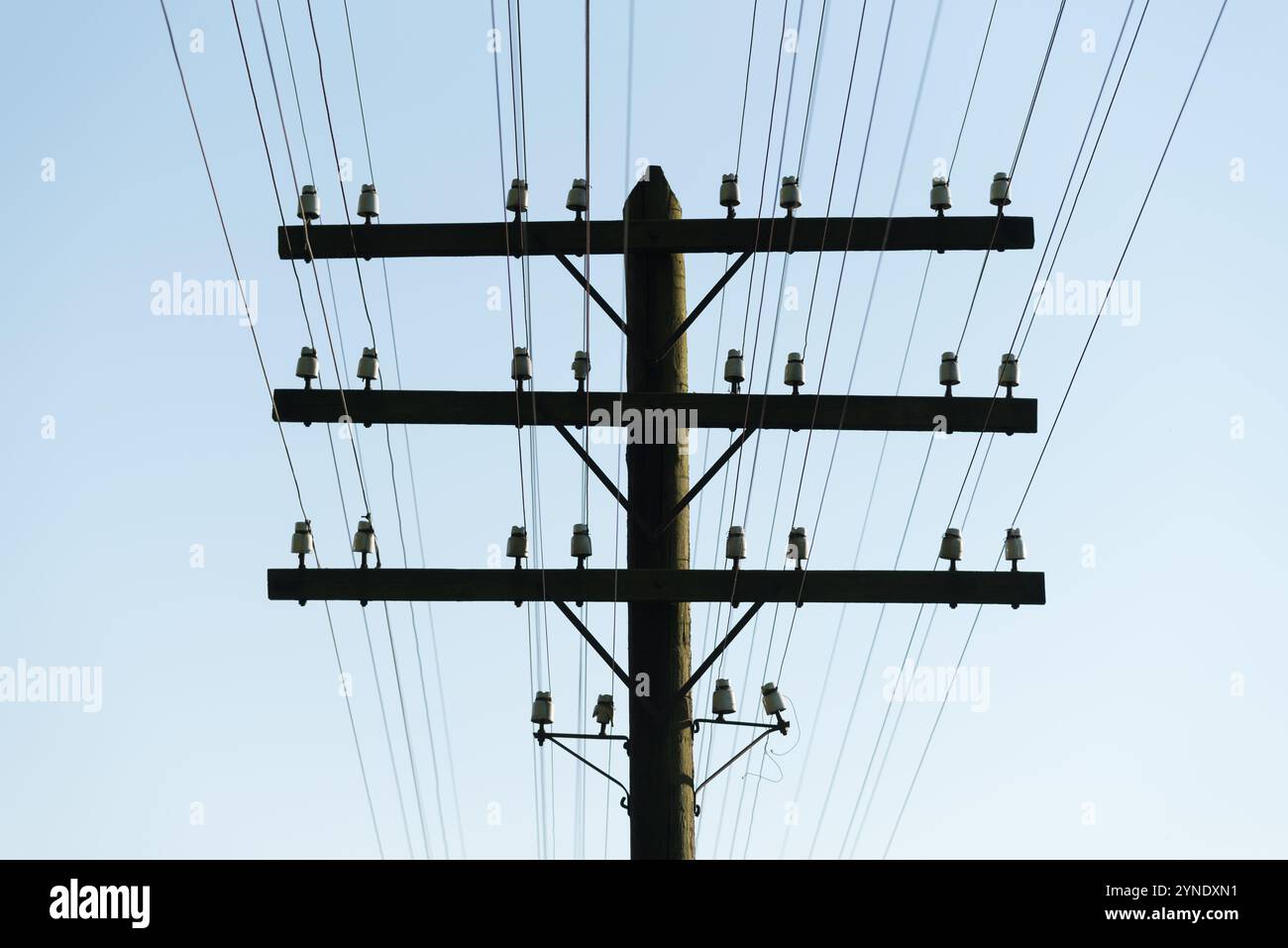 Old wooden pole with electric wires against a clear sky background ...