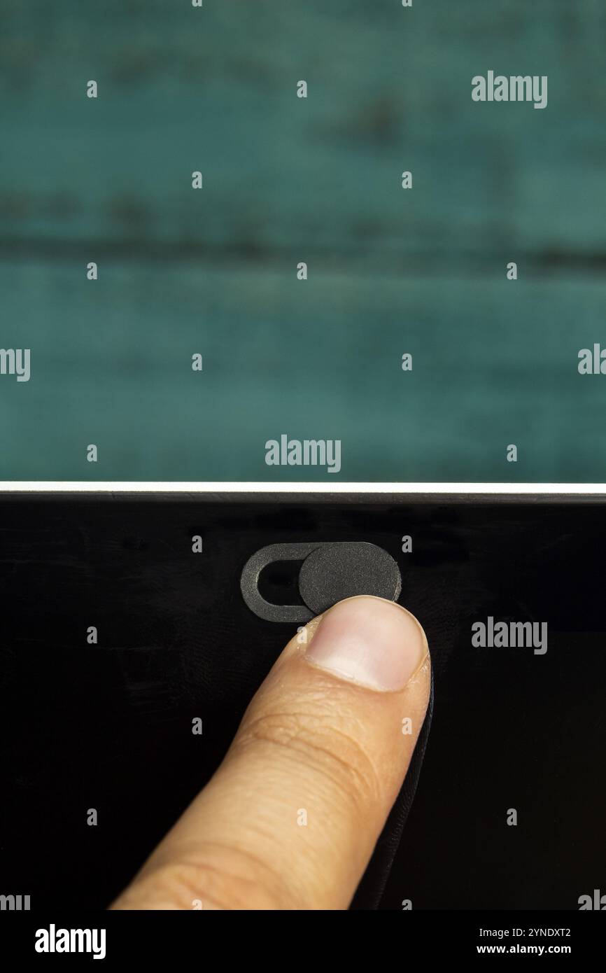 Camera Privacy Cover Slide by a finger with a green wooden wall Stock ...