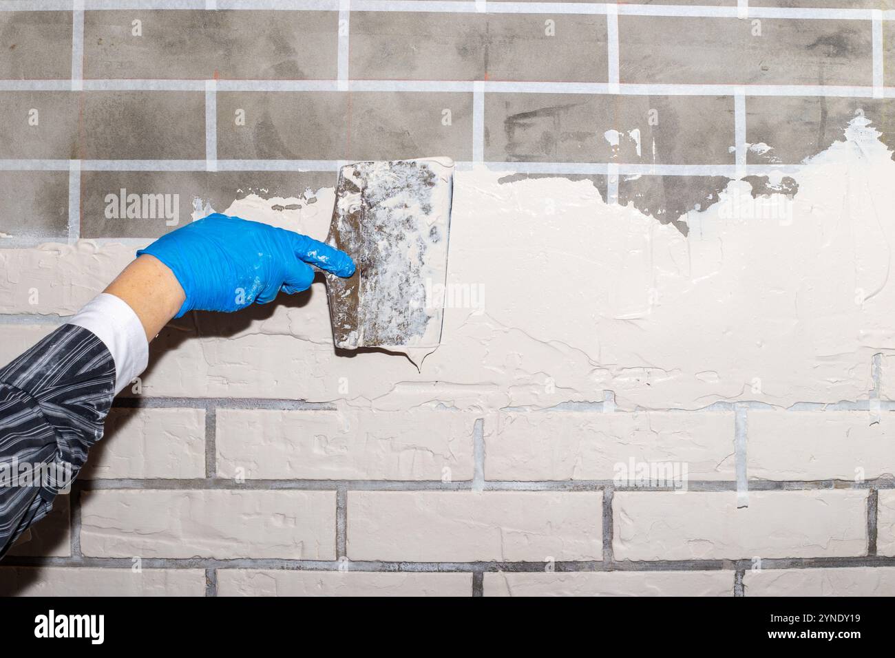Decorative plaster bricks. A woman applies putty to the markings on the ...