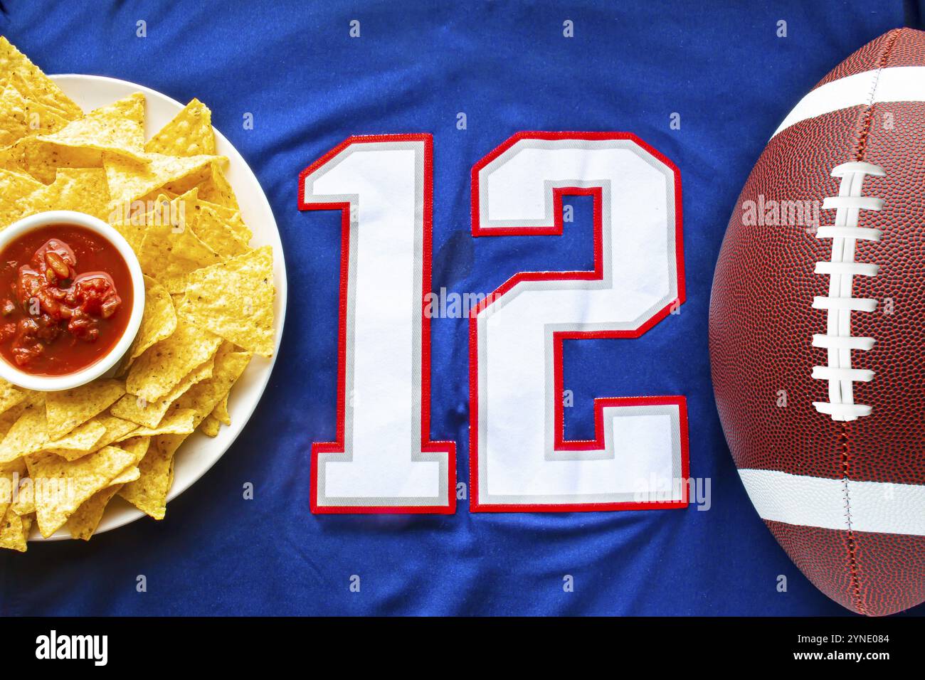 An American football with organic nacho chips and mild salsa on a white ...