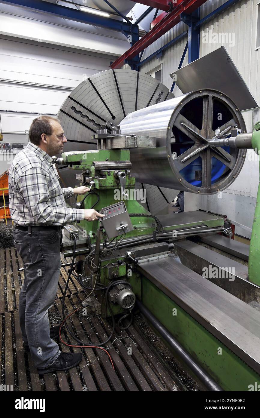 An older employee in the metal industry works on a CNC milling machine ...