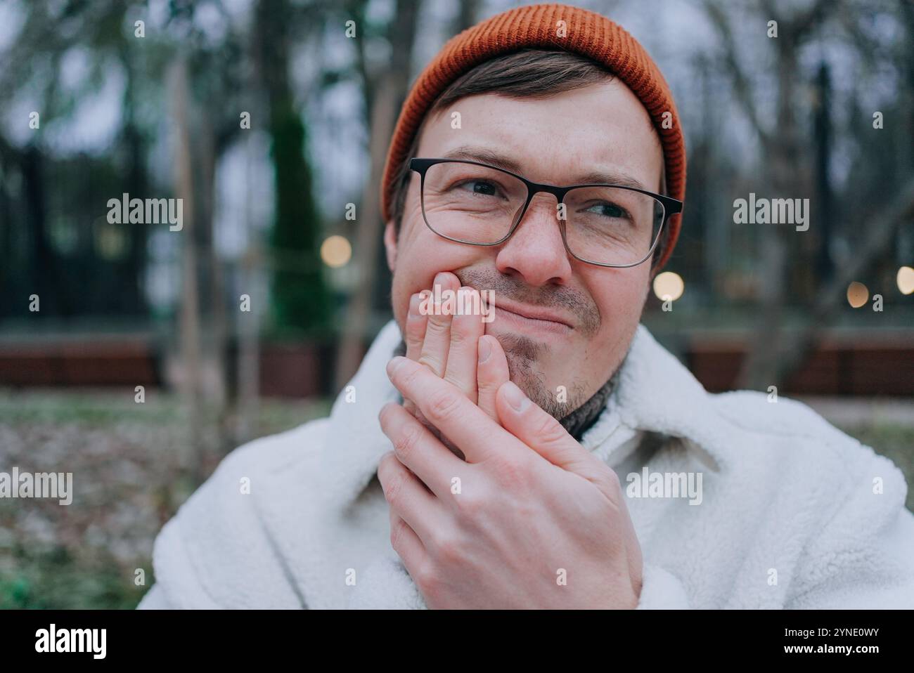 Worried man with a toothache in a park, feeling pain and stress ...