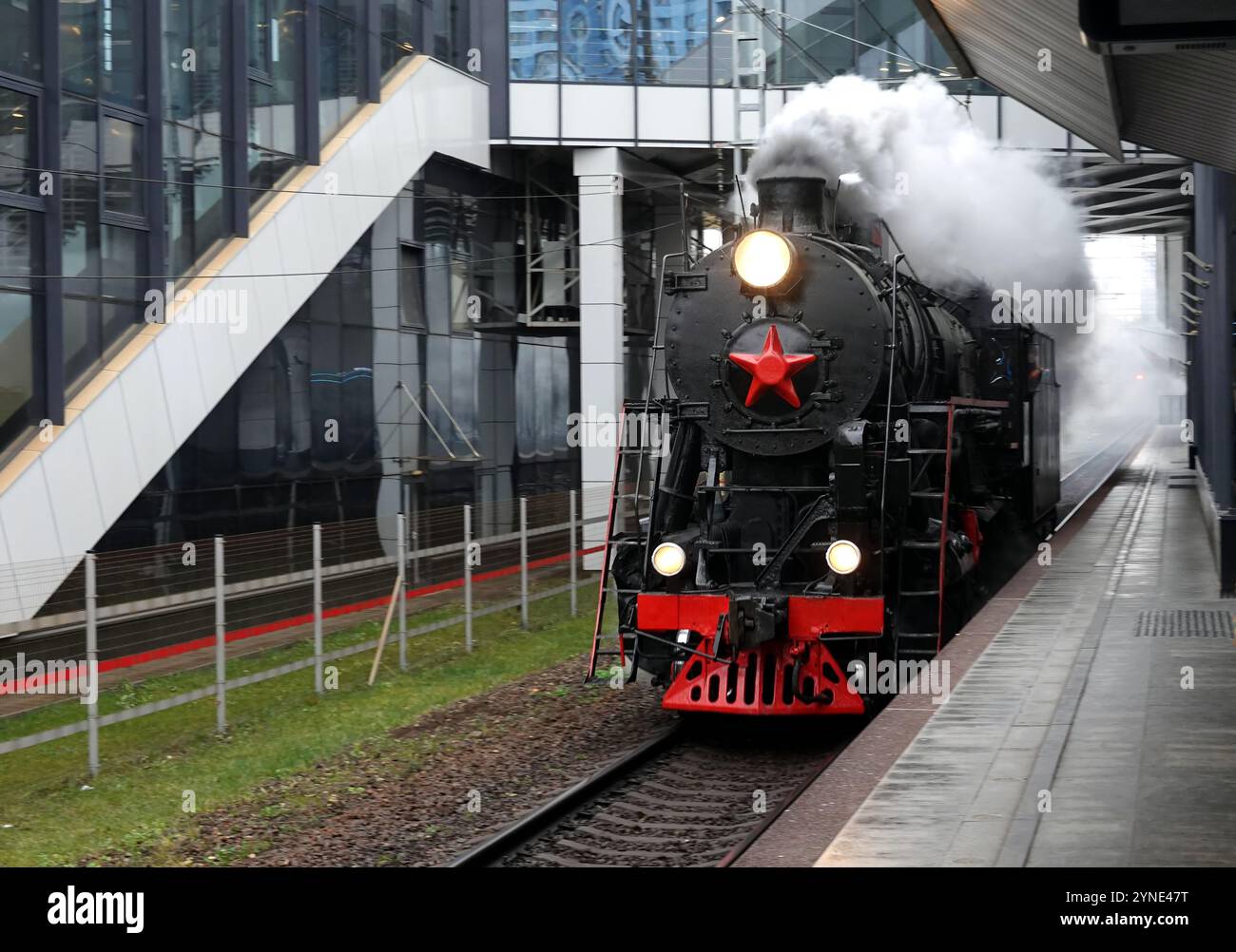 Industrial landscape with old black steam locomotive with red star on ...