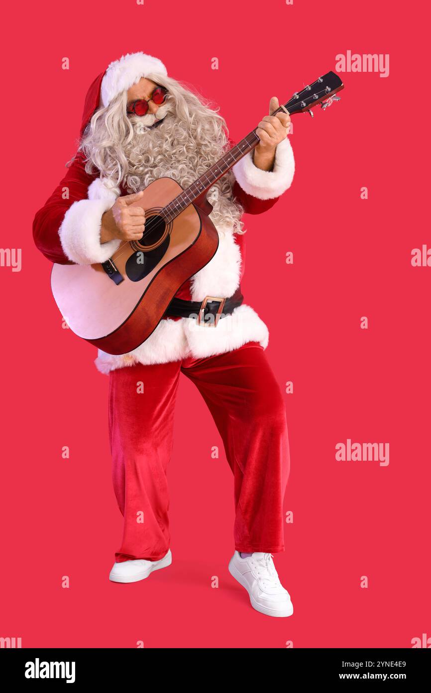 Santa Claus playing guitar on red background Stock Photo - Alamy