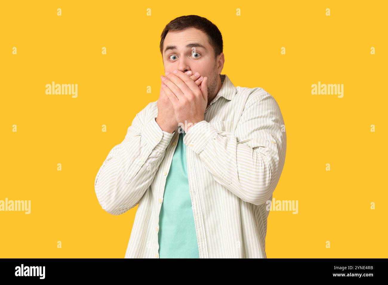 Shocked young man on yellow background Stock Photo - Alamy