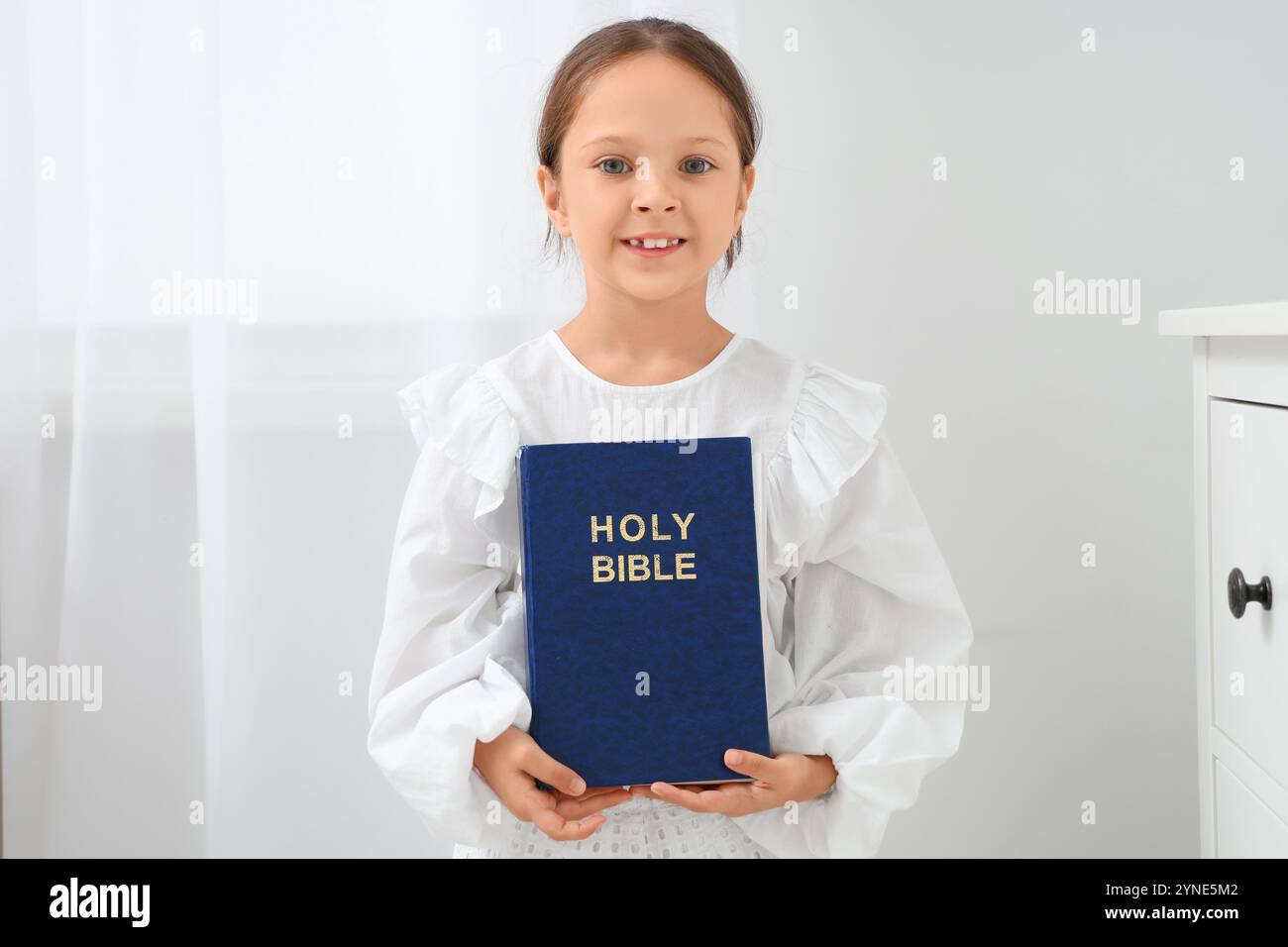 Cute little girl with Bible at home Stock Photo - Alamy