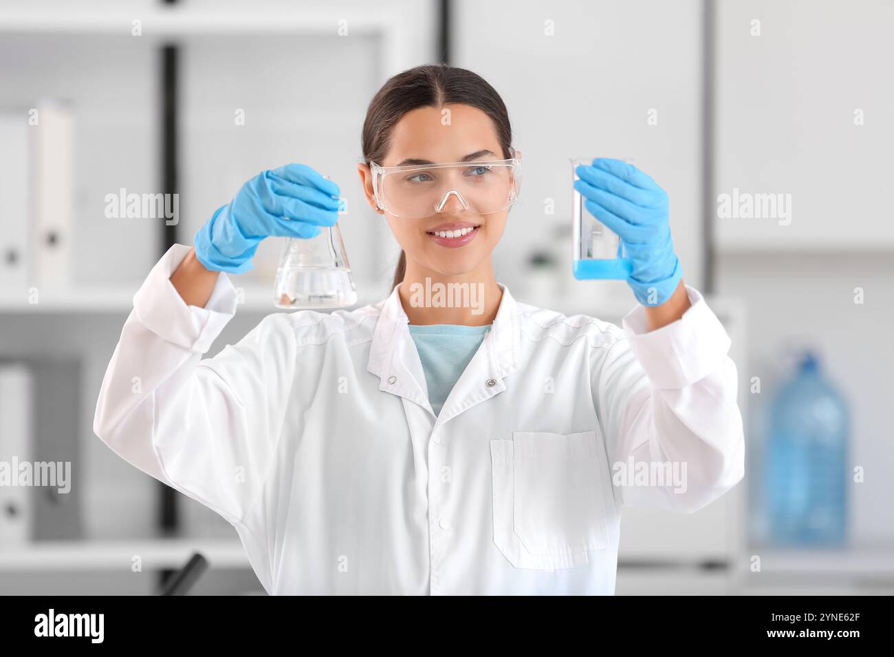 Happy female young scientist with flasks of water samples in research ...