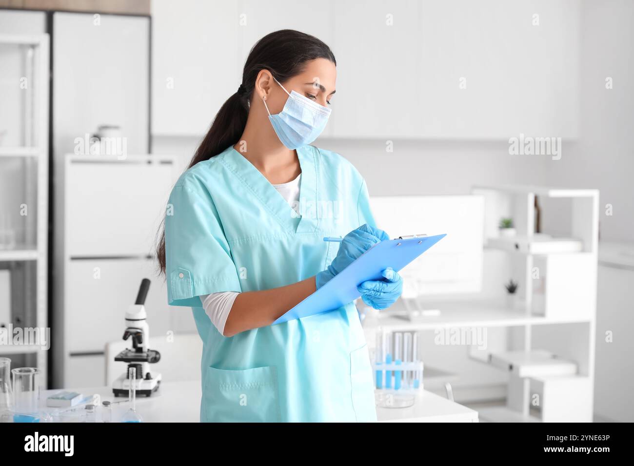 Female young scientist writing on clipboard while examining water ...