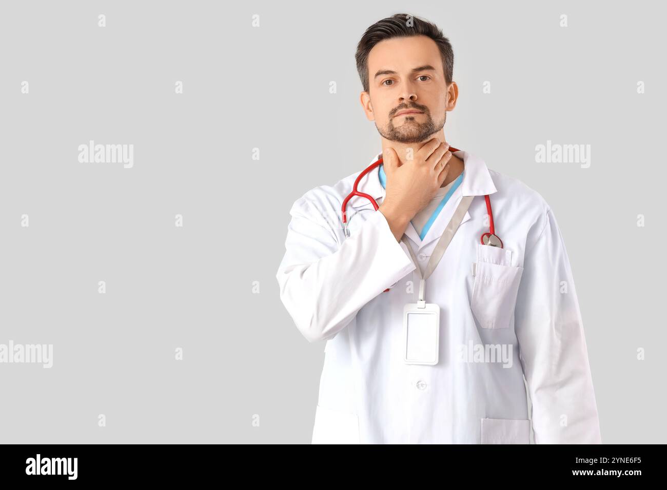 Male endocrinologist self-examining thyroid gland on grey background ...