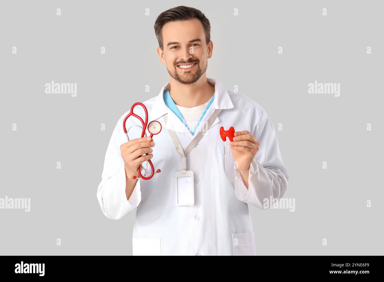 Male endocrinologist with thyroid gland model and stethoscope on grey ...