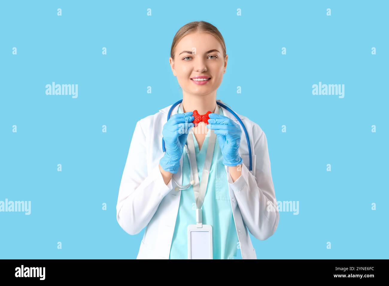 Female endocrinologist with thyroid gland model on blue background ...