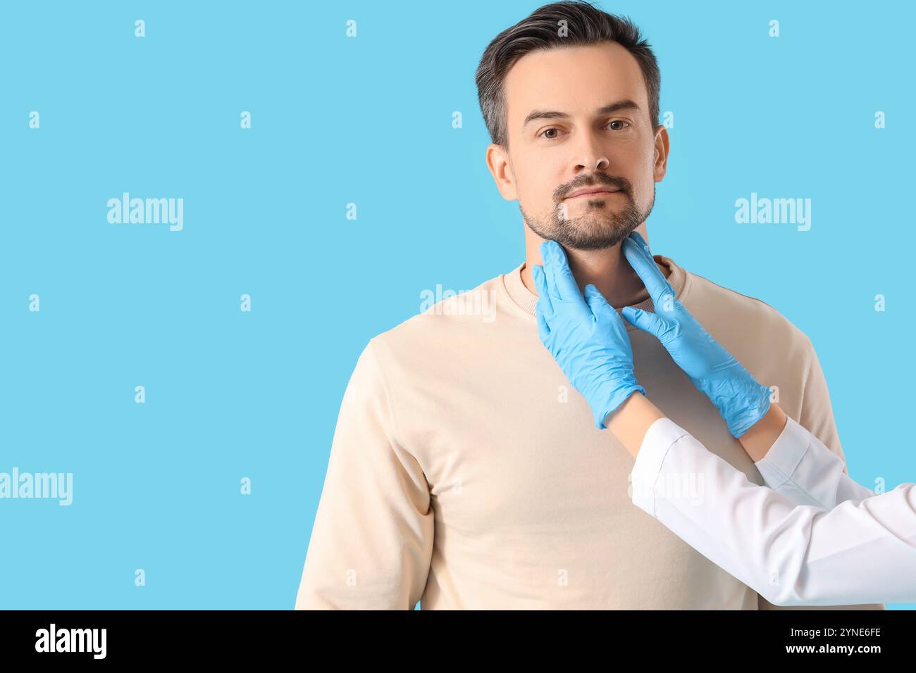 Endocrinologist examining man's thyroid gland on blue background Stock ...