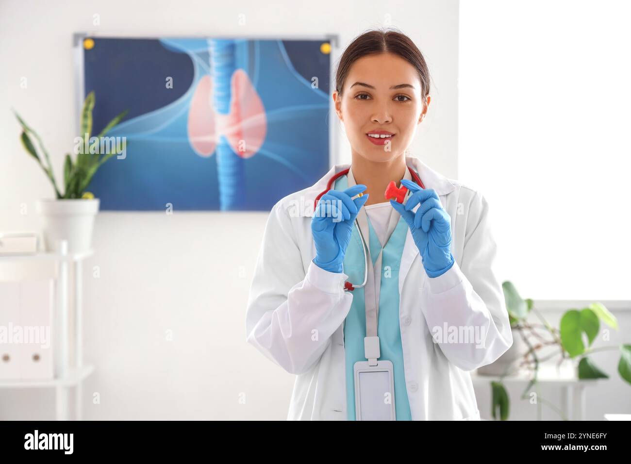 Female Asian endocrinologist with thyroid gland model and pill in ...