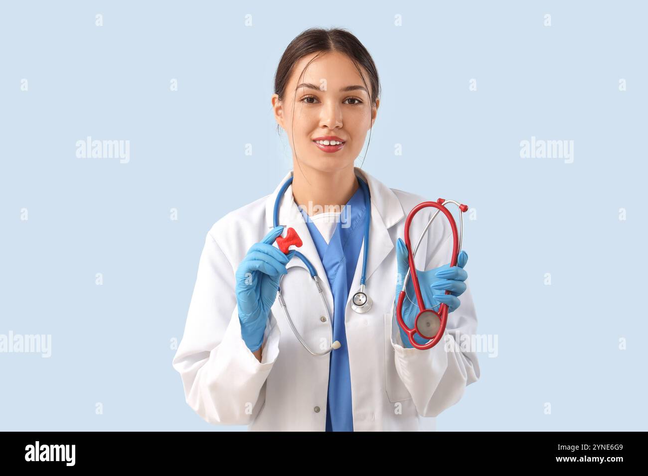 Female Asian endocrinologist with thyroid gland model and stethoscope ...