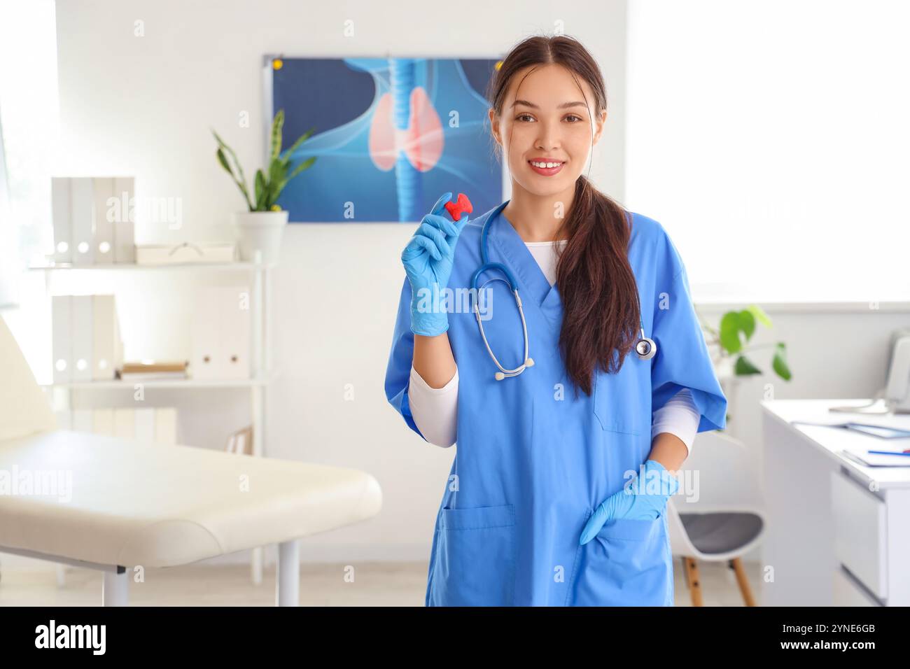 Female Asian endocrinologist with thyroid gland model in clinic Stock ...
