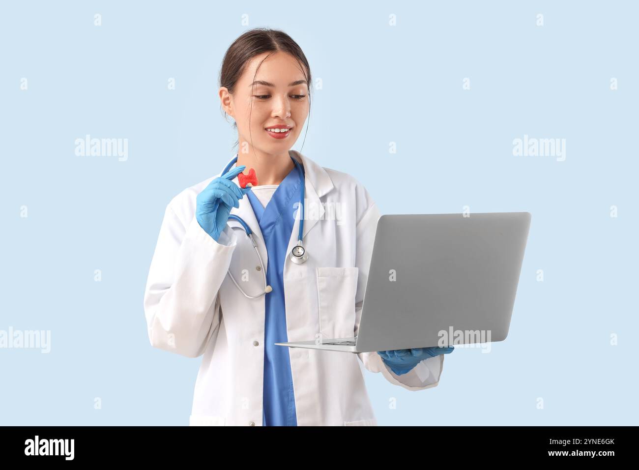 Female Asian endocrinologist with thyroid gland model and laptop on ...