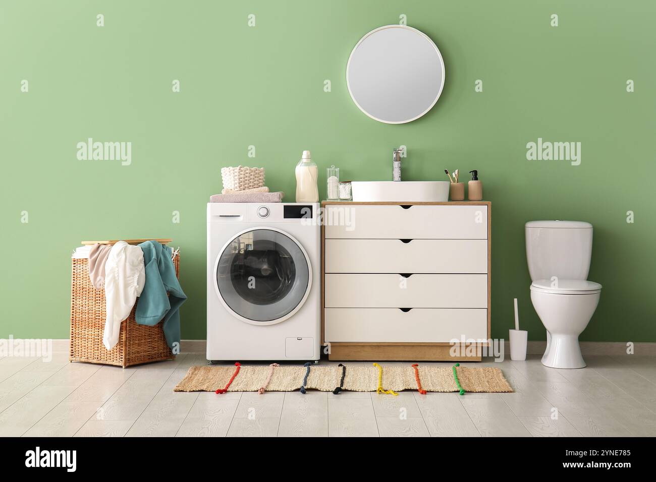 Modern washing machine, toilet bowl, chest of drawers and basket with ...