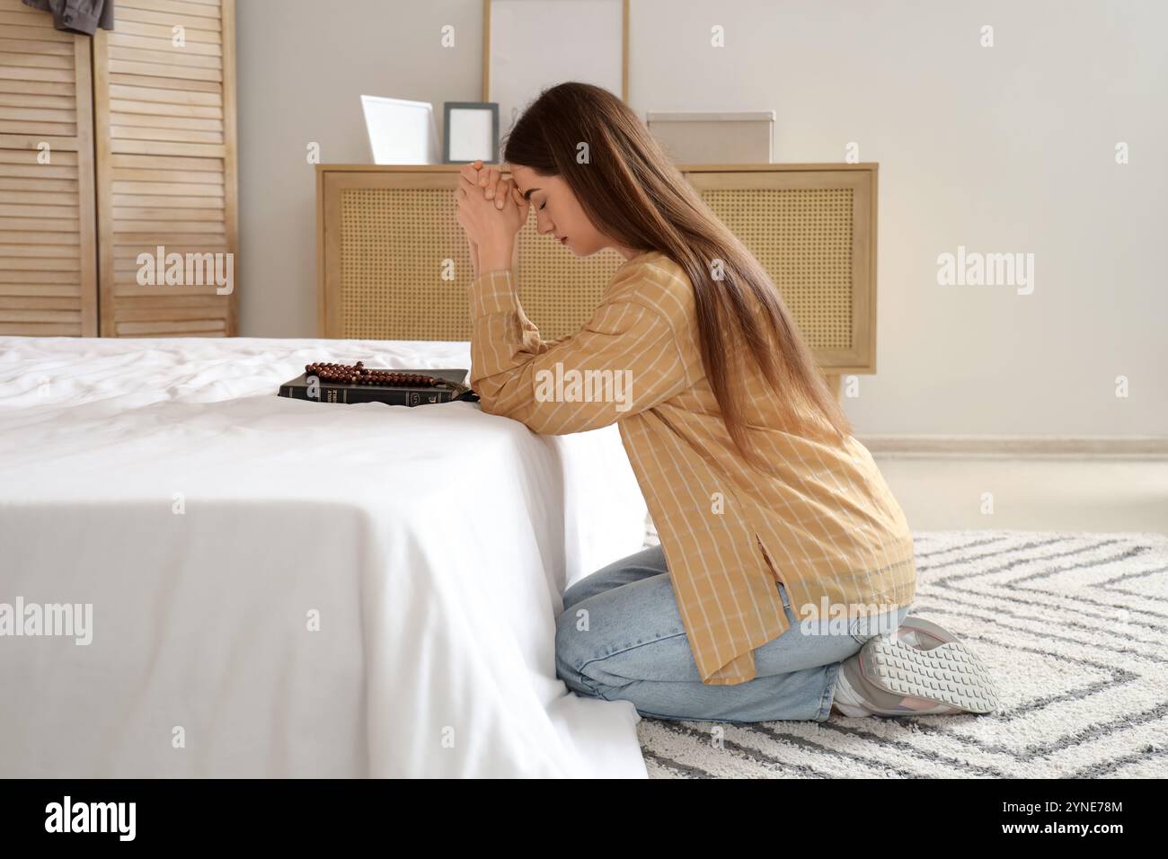 Young woman praying with Holy Bible on bed in bedroom Stock Photo - Alamy