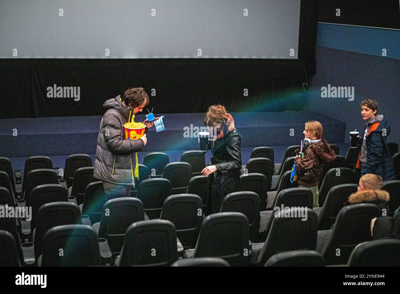 family with popcorn and drinks looking for their seats before watching ...