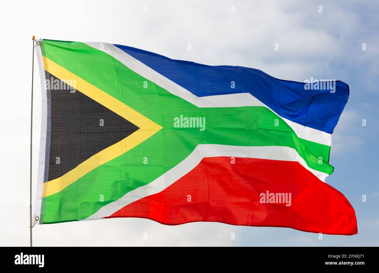 Against background of cloudy sky, South African flag flapping in wind ...
