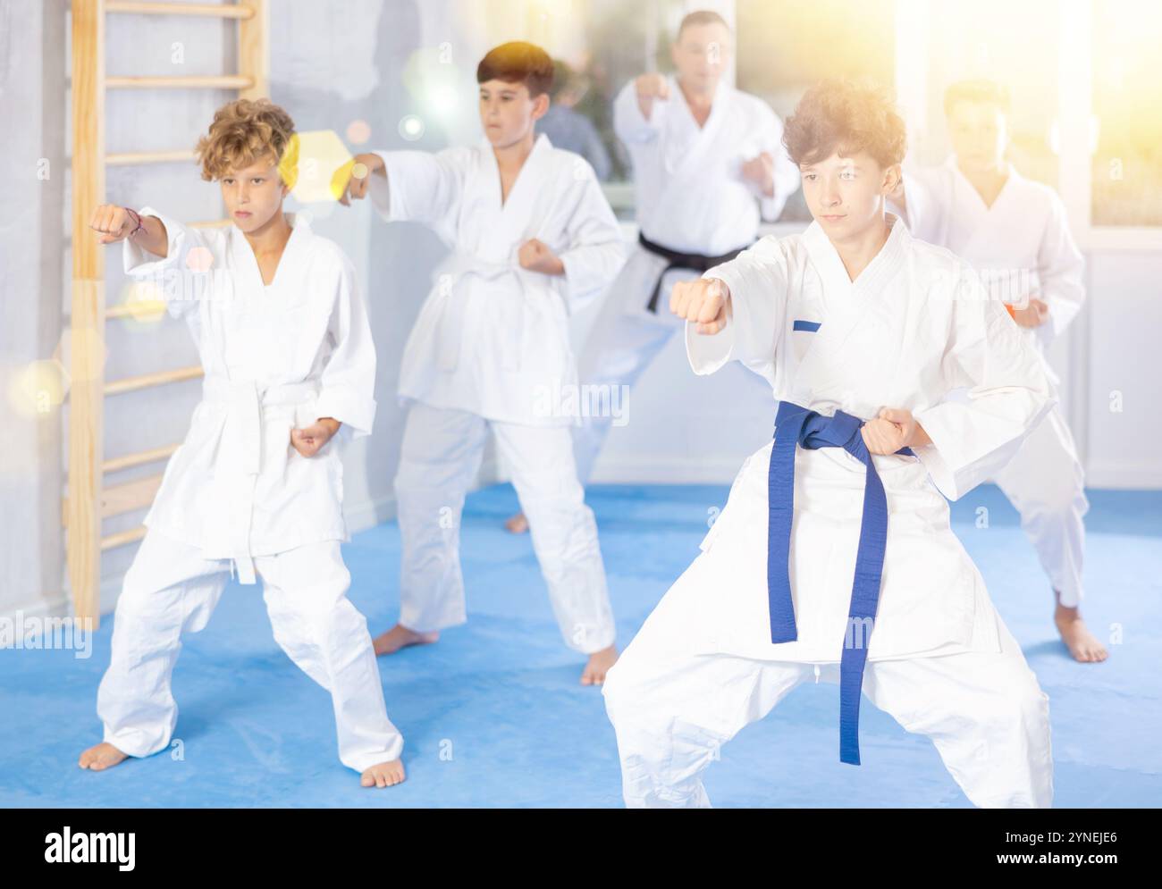 Teenage boy with group of karate practitioners performing kata routines ...