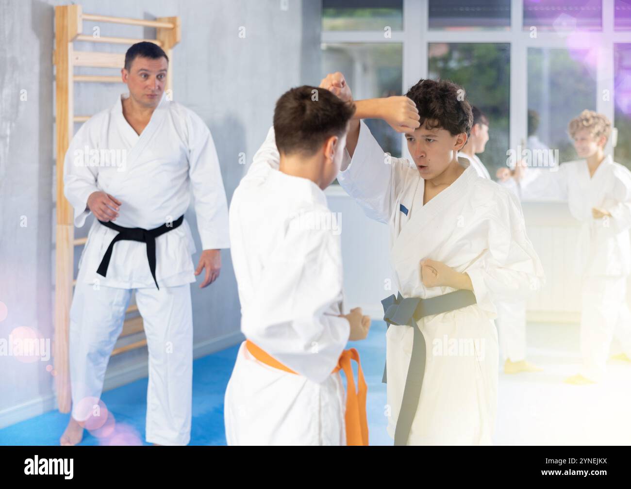 Teenage boys in karate uniforms practicing hand strikes during sparring ...