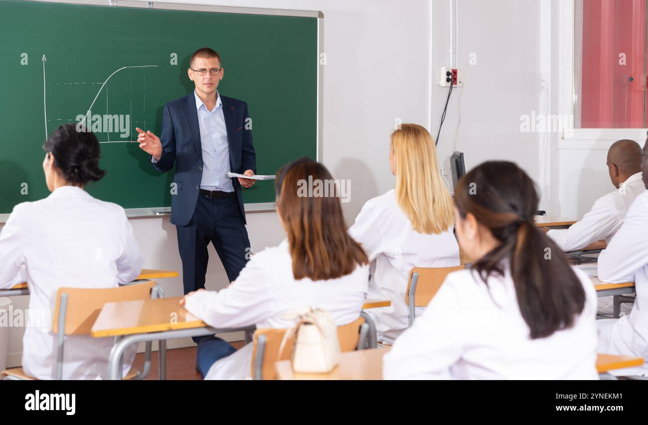Professor explaining function graph to adult students in auditorium ...