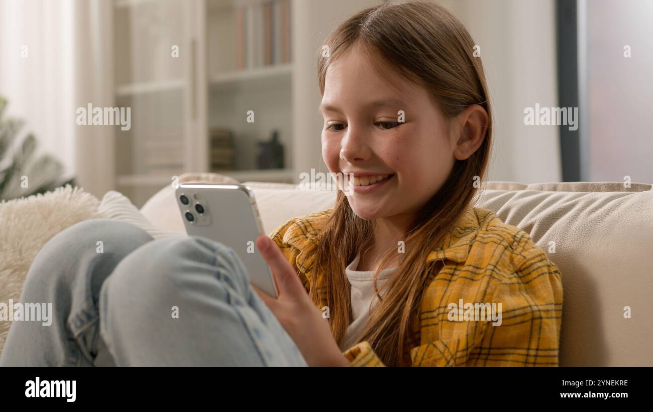 Smiling happy kid girl sending message checking email using mobile ...