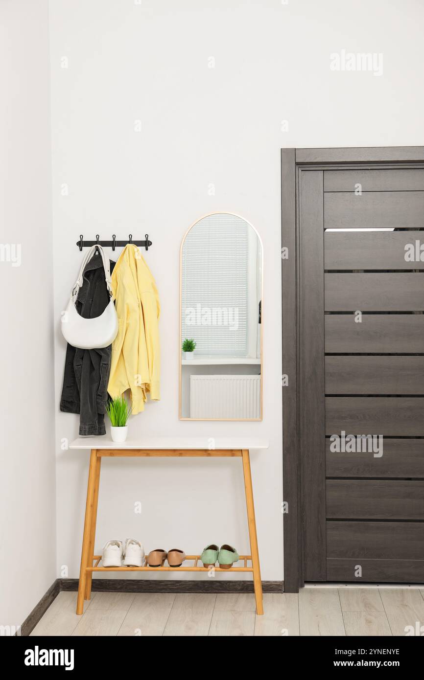 Mirror, rack with clothes and shoe storage bench in hallway. Interior ...