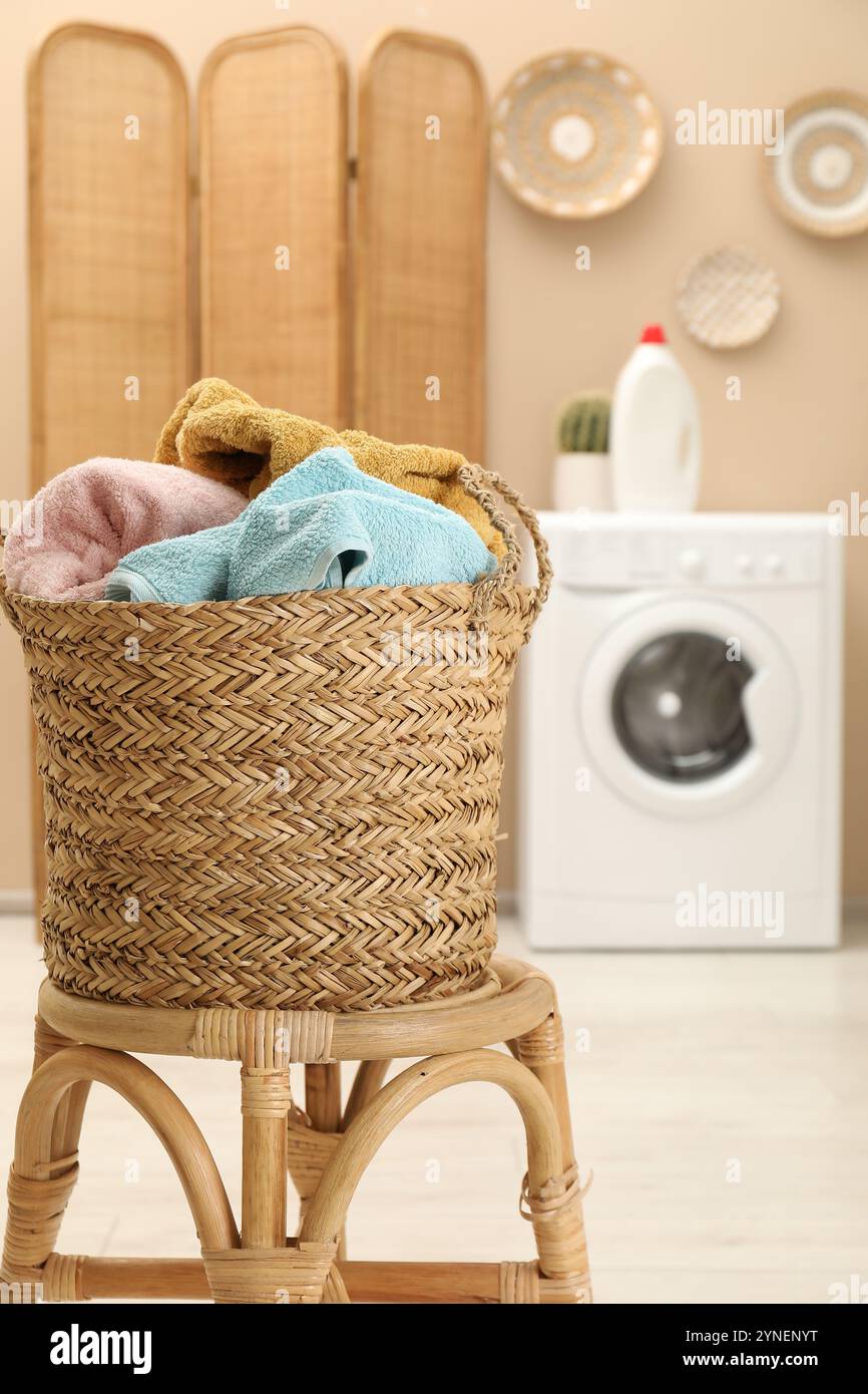 Wicker basket full of laundry on chair in bathroom Stock Photo - Alamy