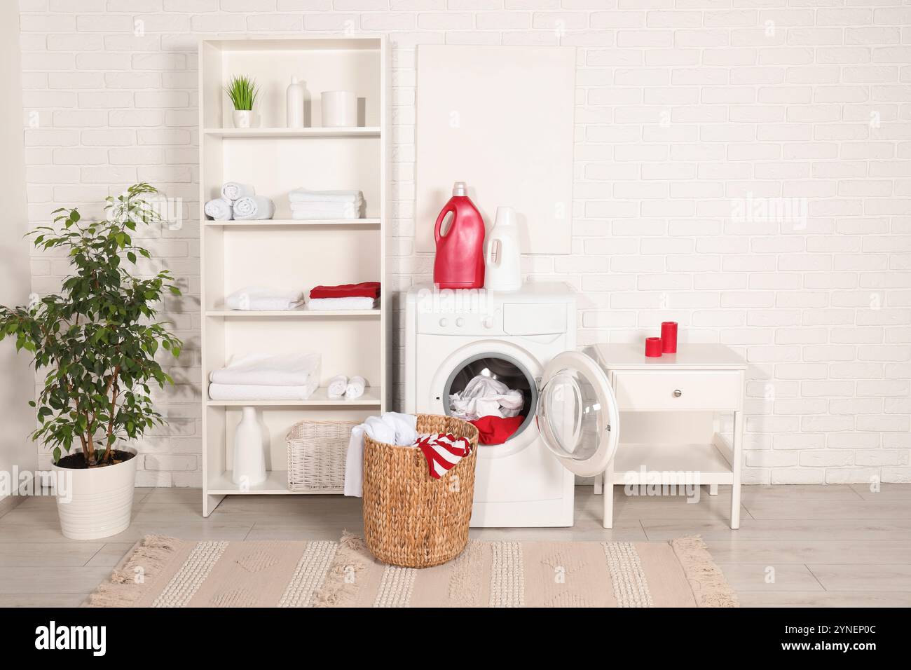 Washing machine, detergents and basket with laundry in room Stock Photo ...