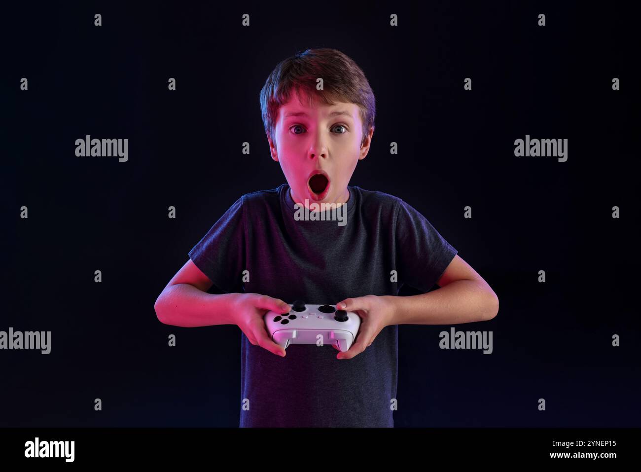 Cute little boy playing video game with controller on black background ...
