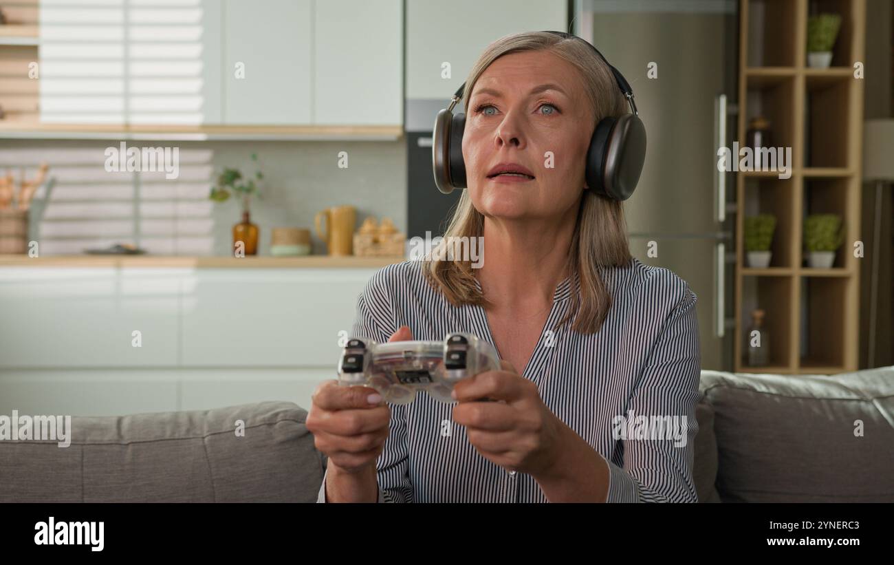 Funny smiling mature caucasian woman playing video game console in ...