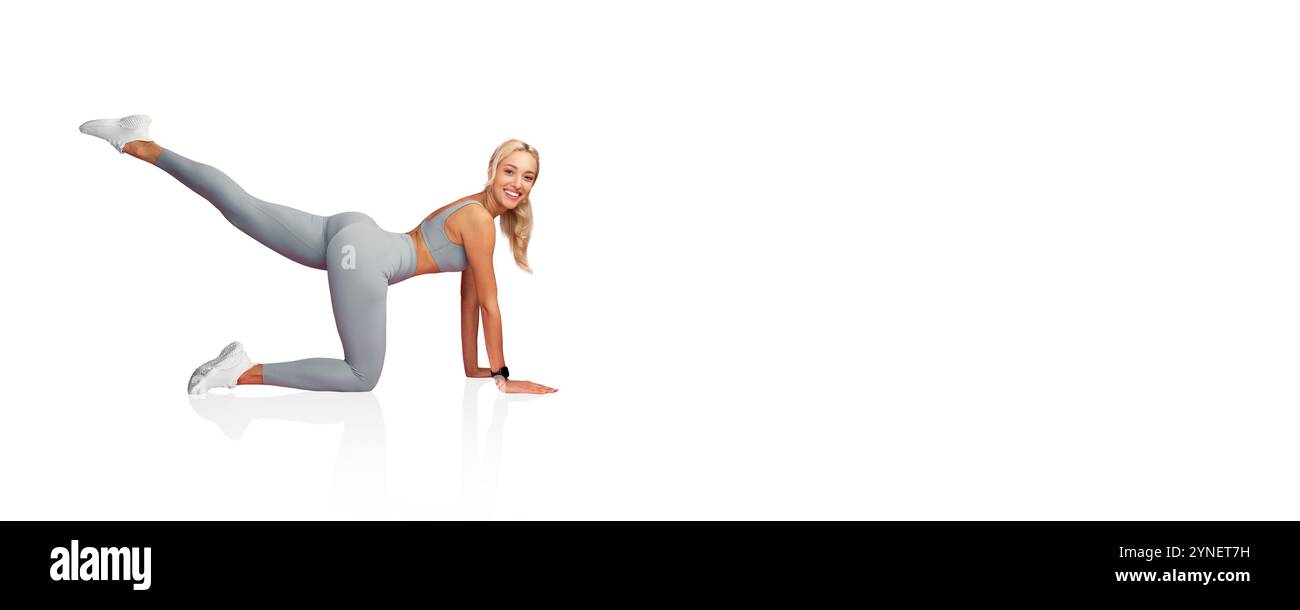 Woman exercising on all fours while lifting one leg in workout studio ...