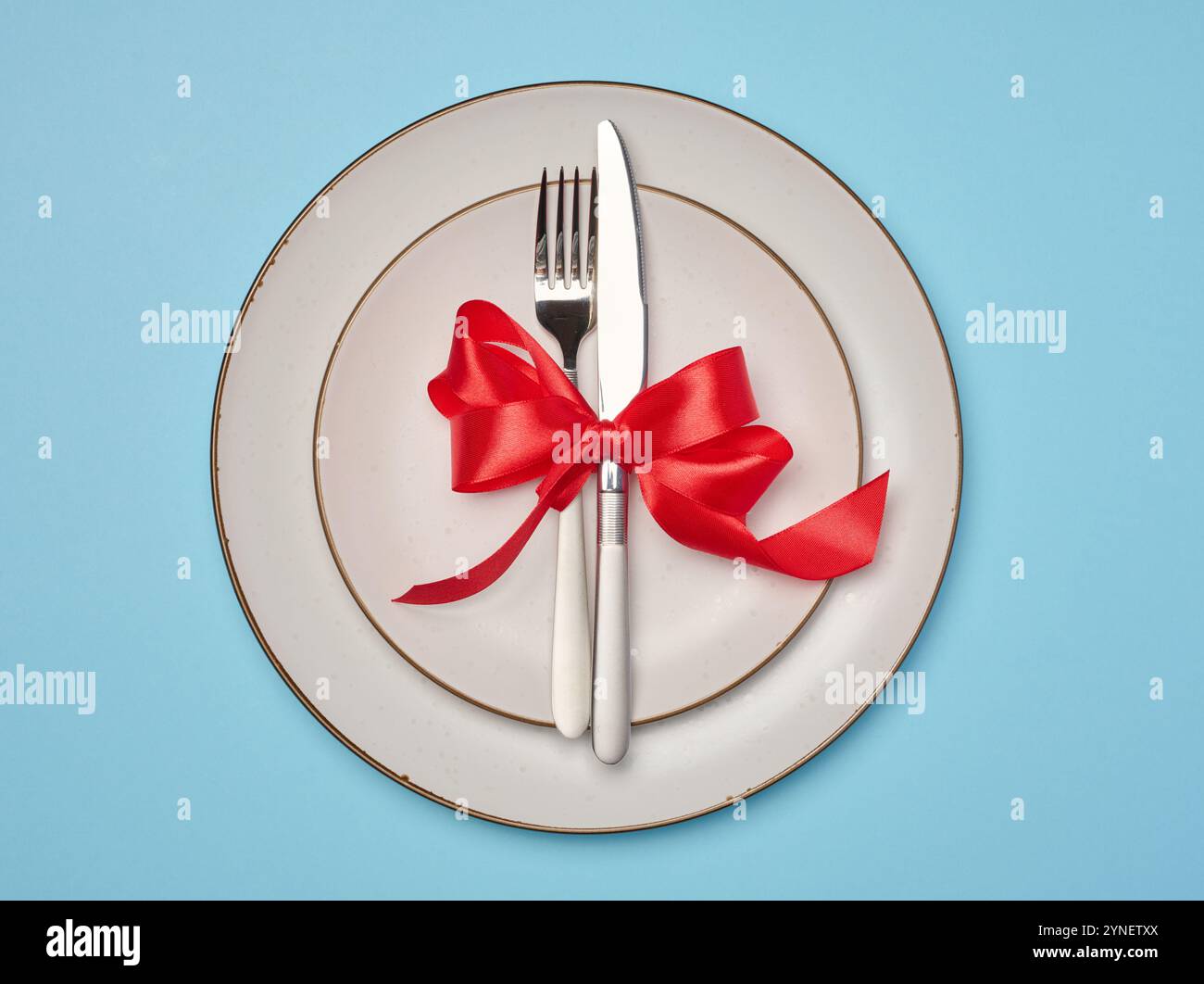 Round white plate and tied with red bow view with knife on yellow ...