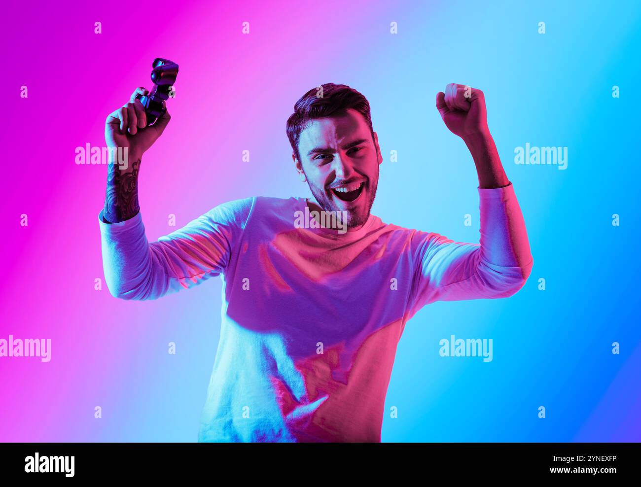 Winning in computer game. Man raises hands with joystick, celebrating ...