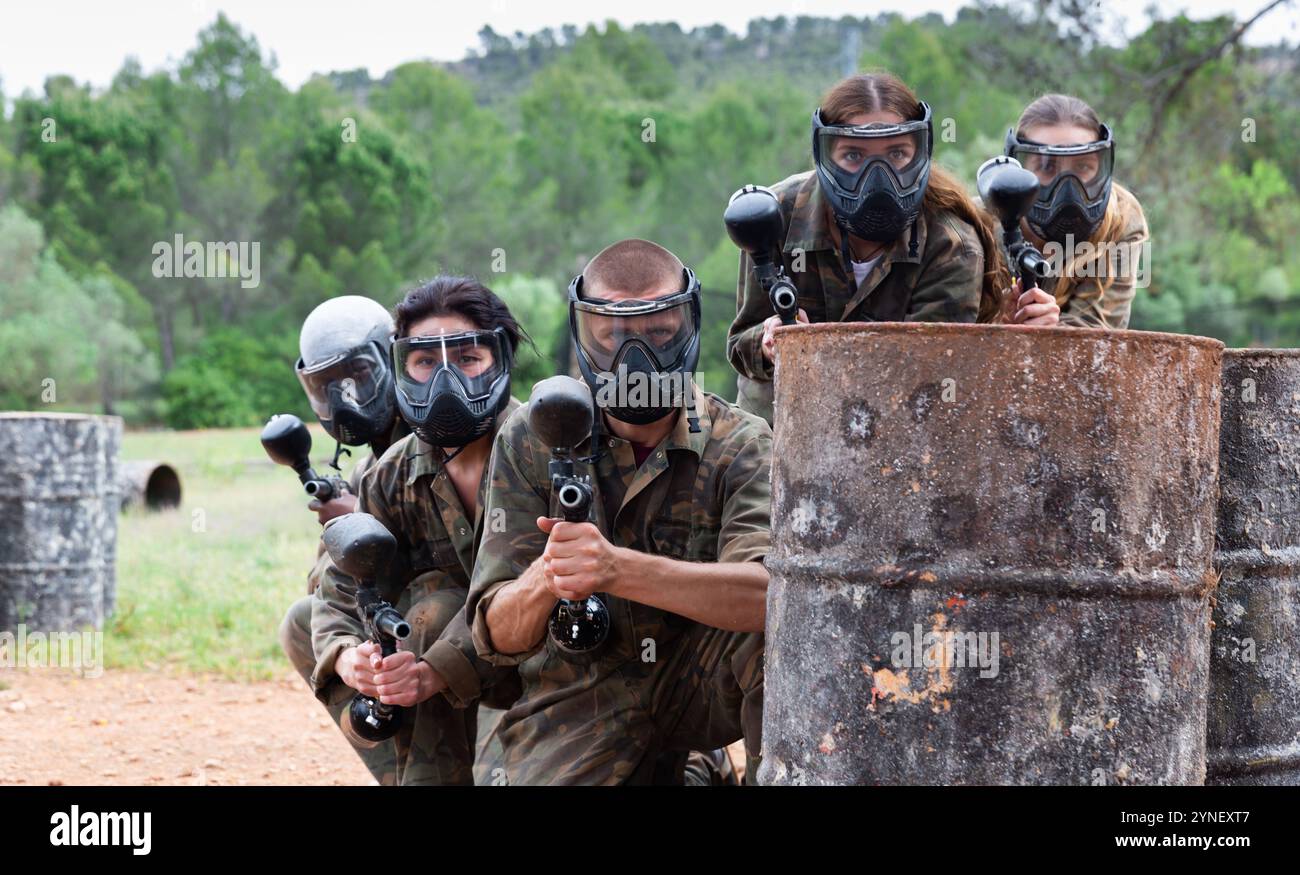 Group of people in full gear playing paintball on shooting range ...