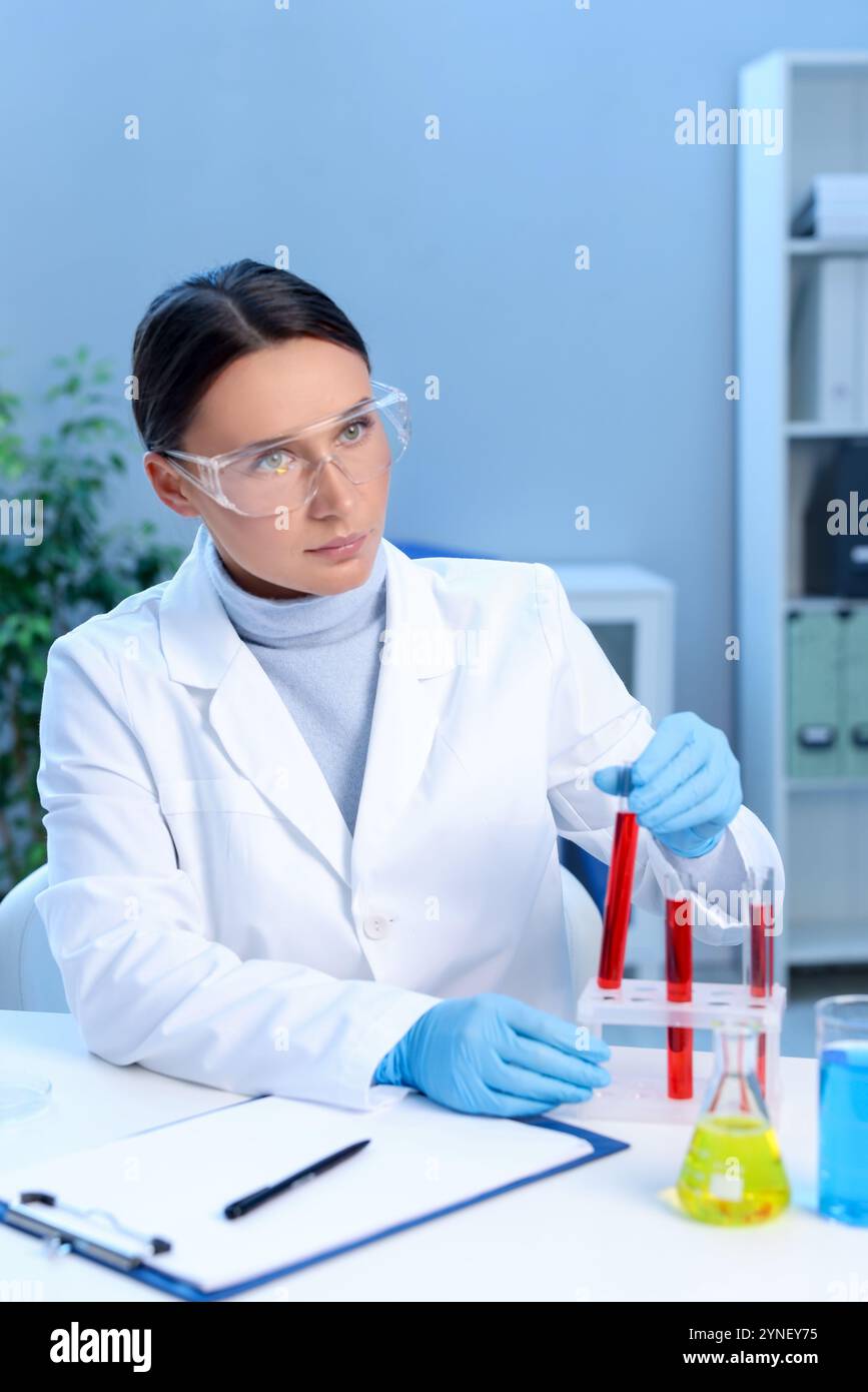 Laboratory testing. Doctor taking test tube with blood sample at table ...