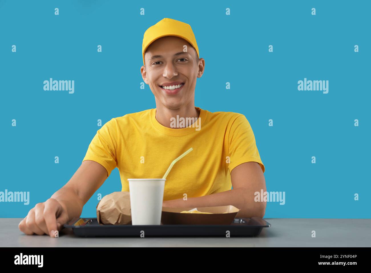 Fast-food worker with order at counter against light blue background ...