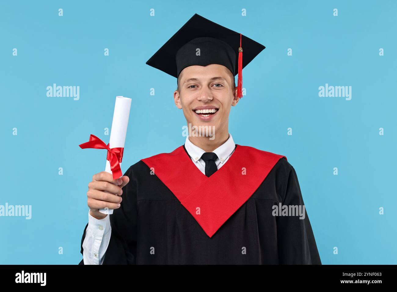 Happy student with diploma after graduation on light blue background ...