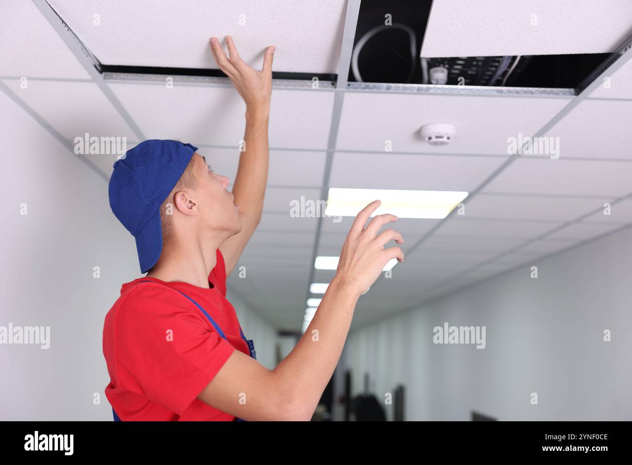Suspended ceiling installation. Builder working with PVC tile indoors ...