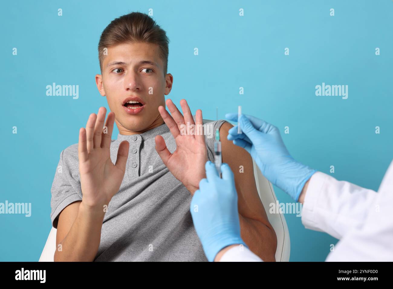 Needle phobia. Scared man making stop gesture near doctor with syringe ...
