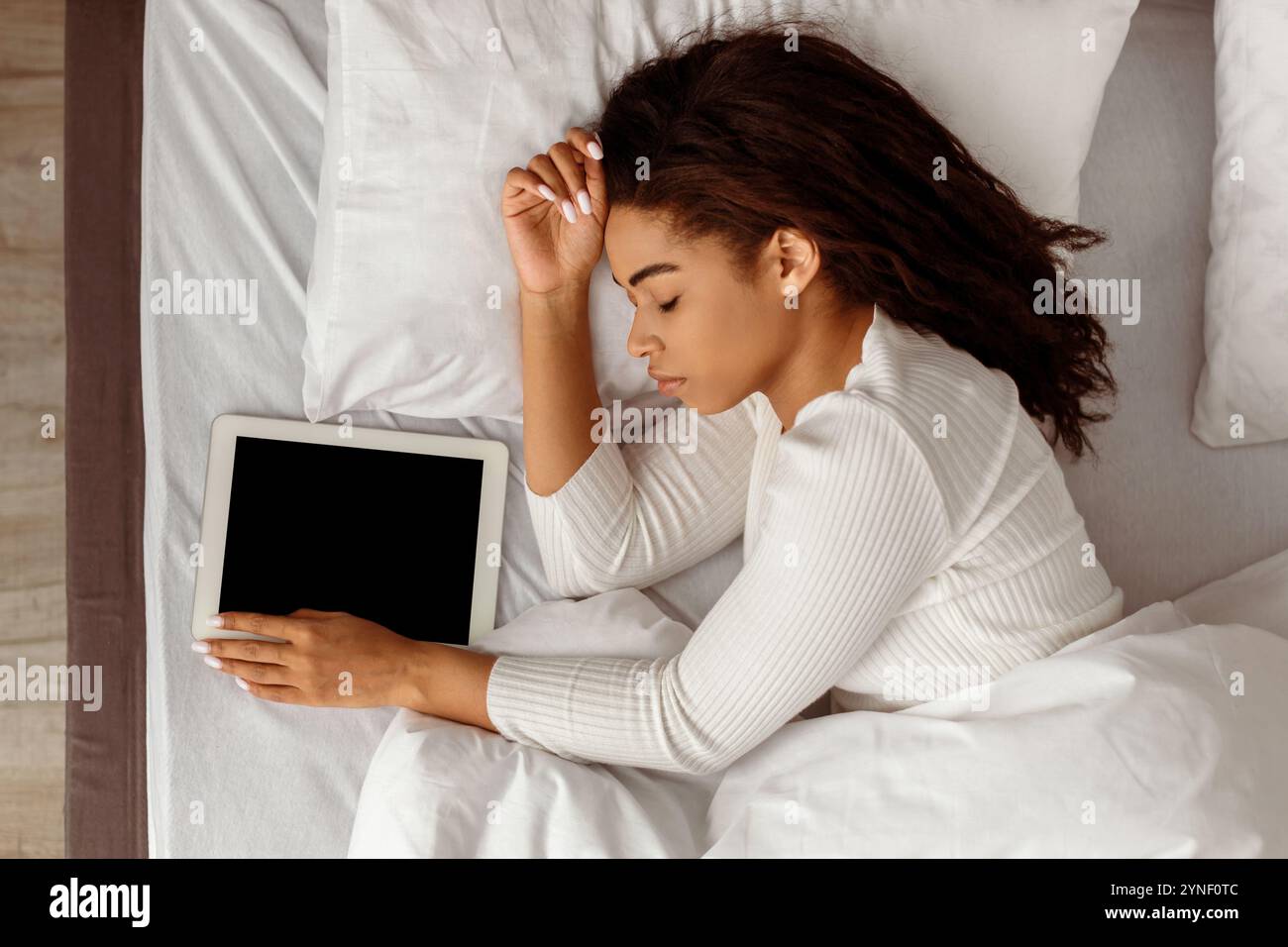 Black woman lying in bed, sleeping and holding tablet Stock Photo - Alamy