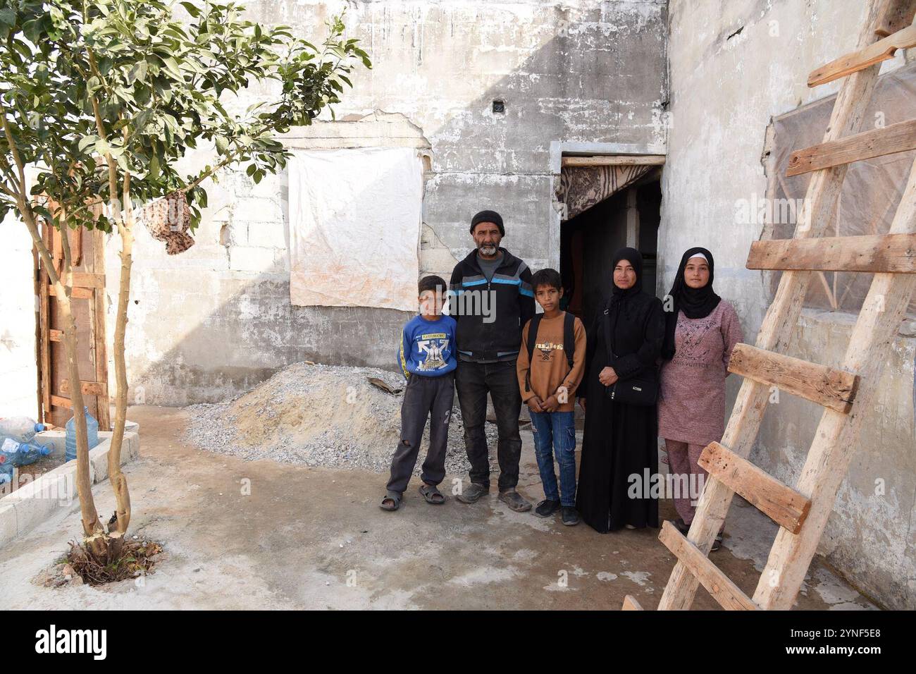 Homs, Syria. 25th Nov, 2024. Zakaria Suleiman Alloush (2nd L), who fled ...